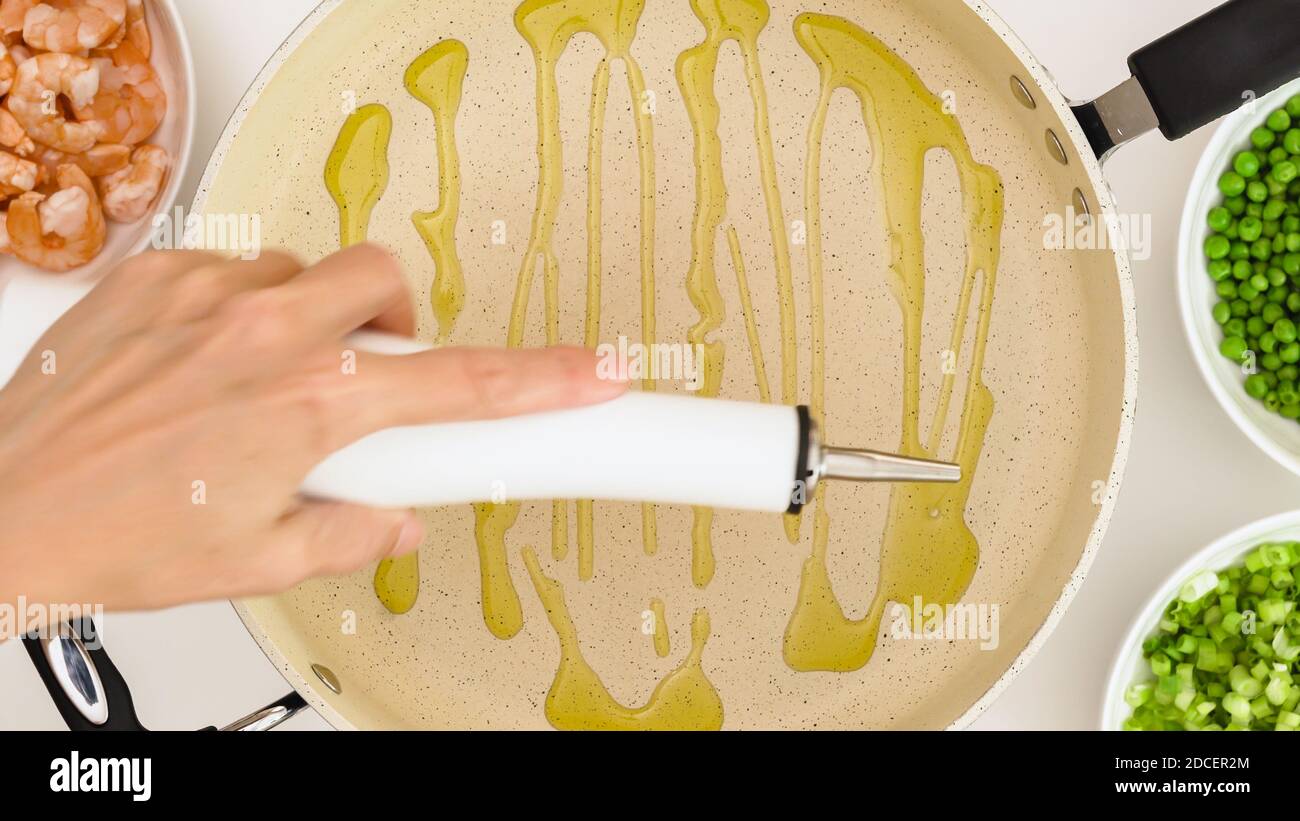 Woman pouring olive oil into frying pan. Cooking shrimp and vegetable ...