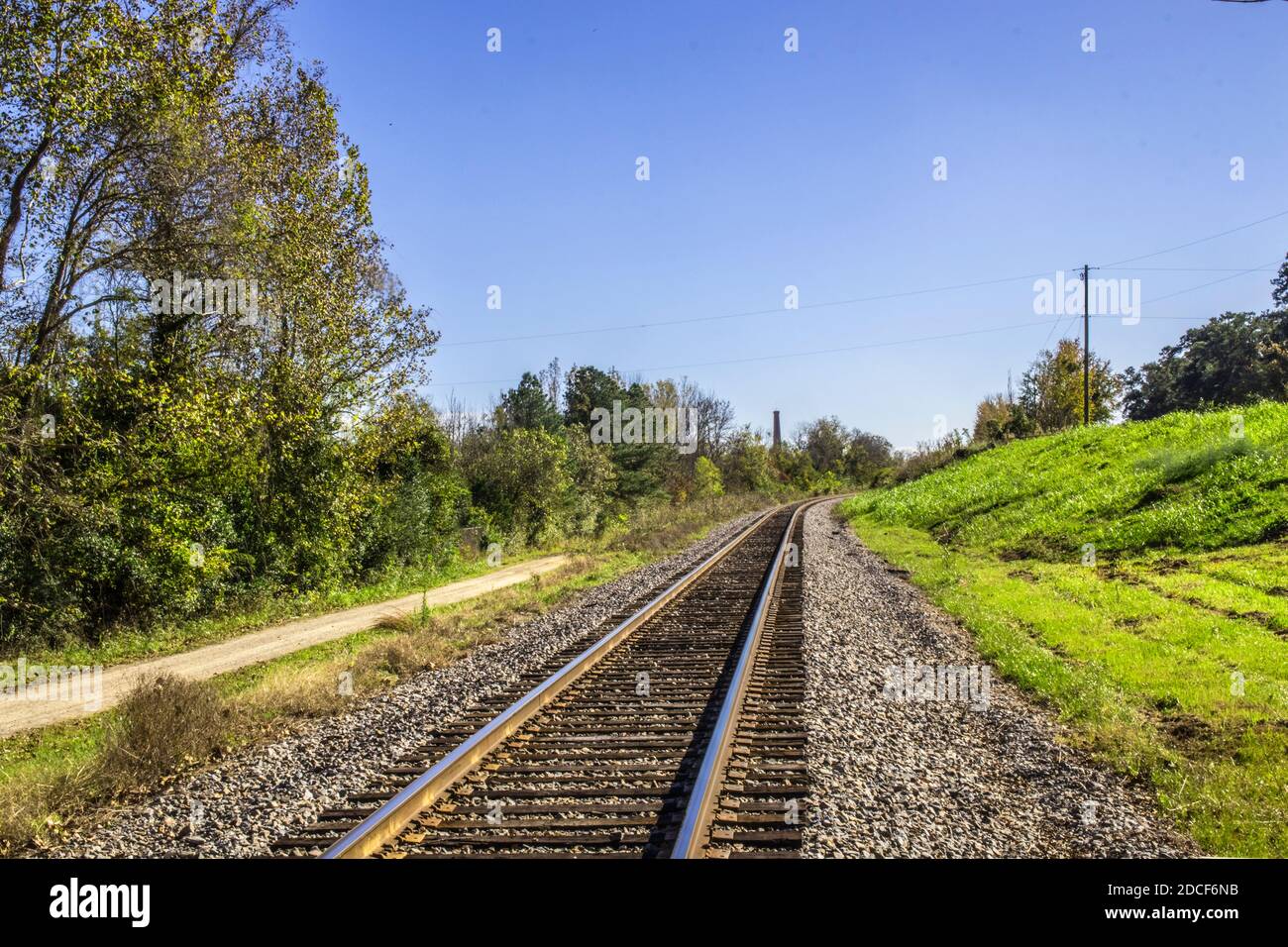 View of train tracks fading into the distance and green grass and blue ...