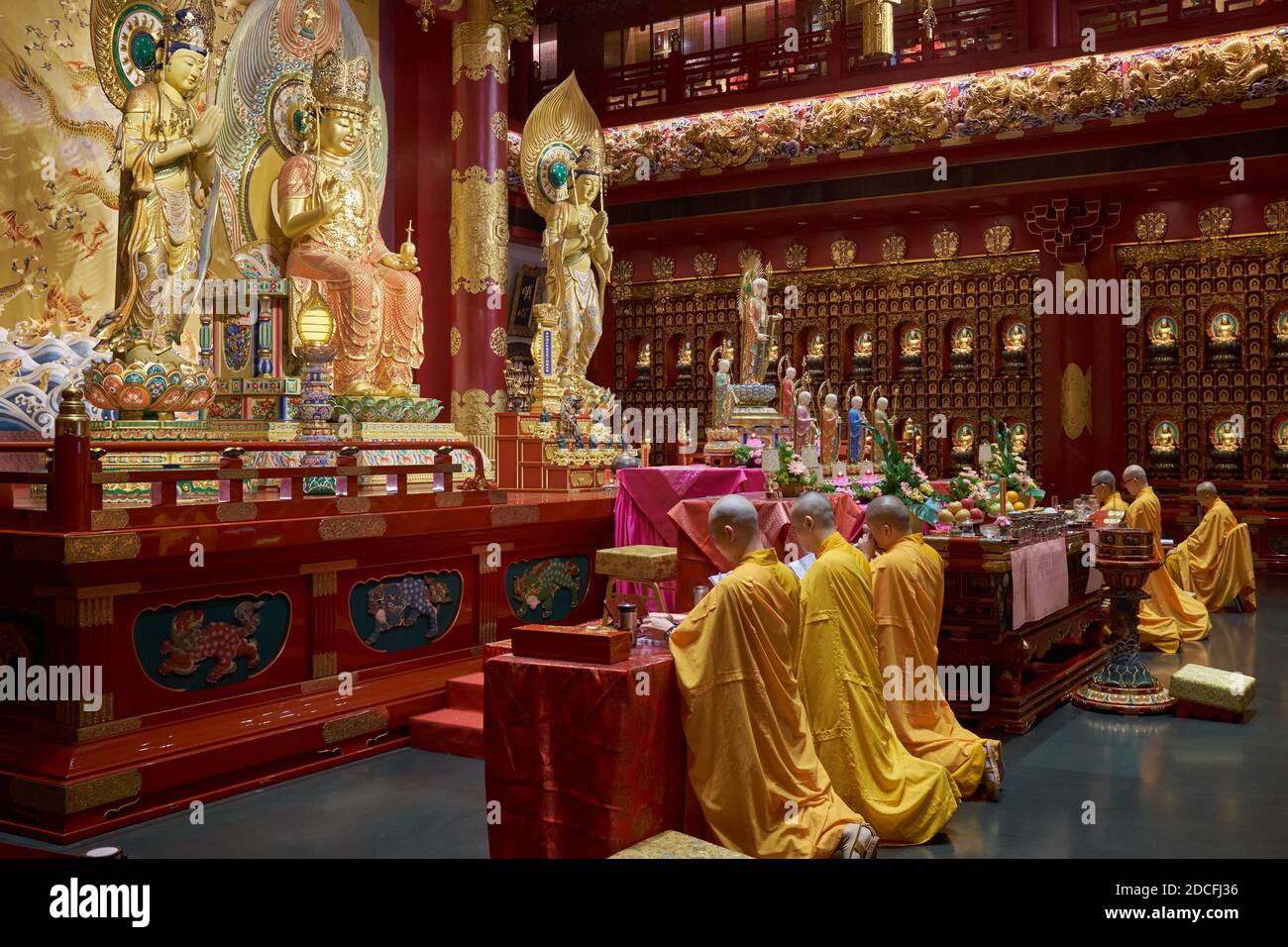 Yellow-robed Buddhist monks conducting prayers in the ornate prayer ...