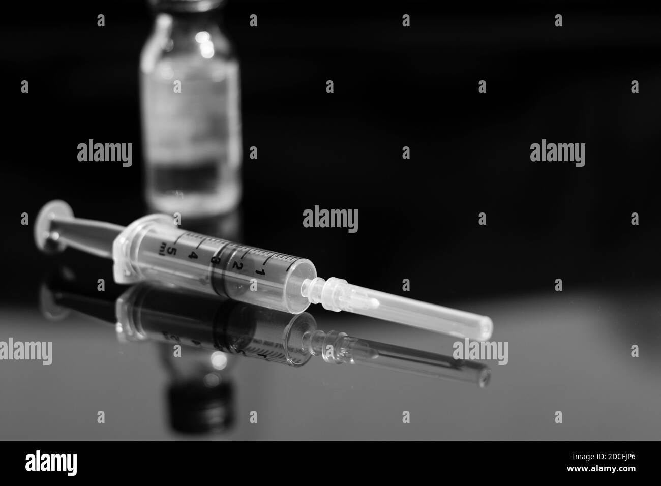 monochrome photo of selective focus on injection syringe and bottle on ...