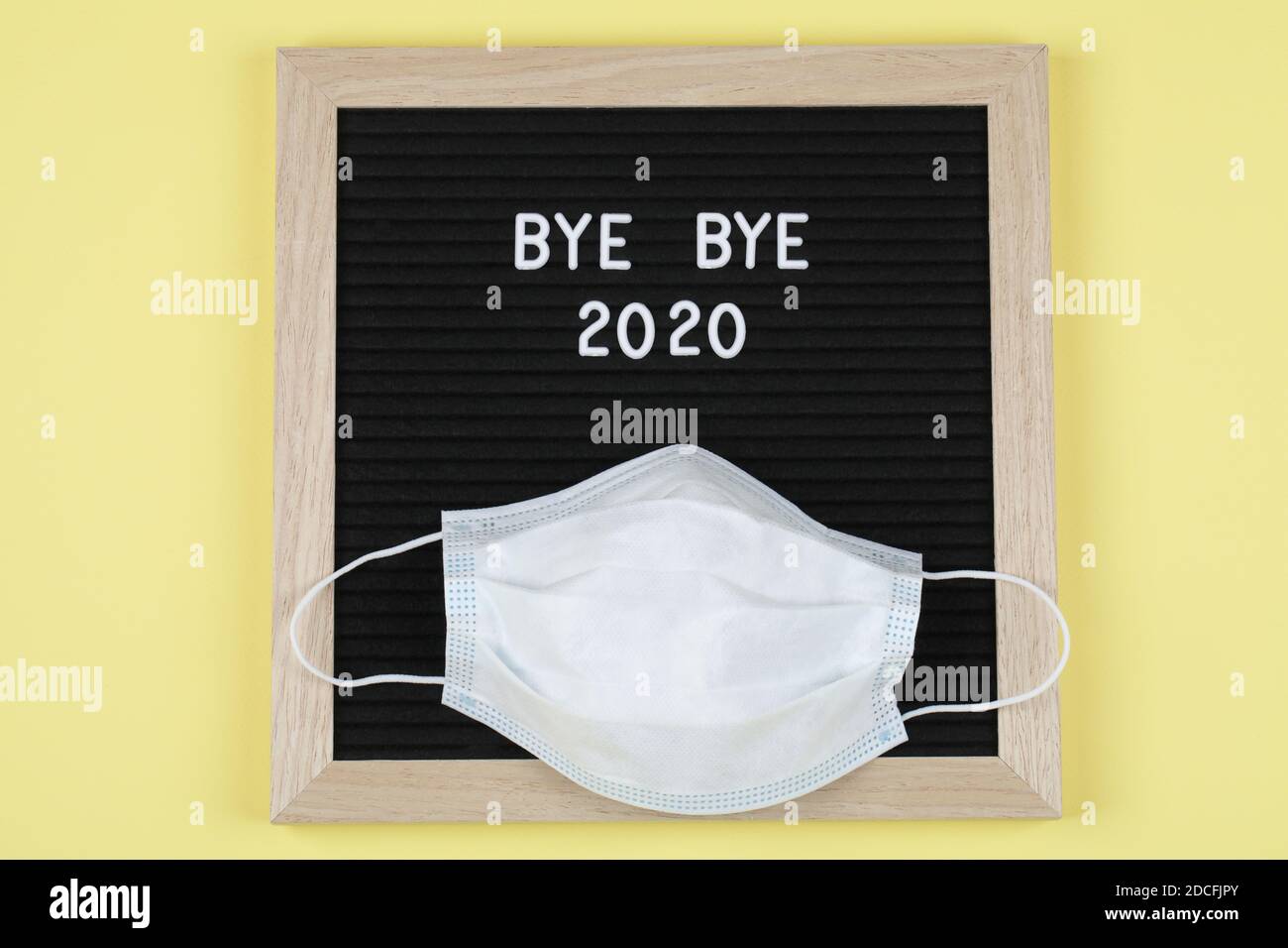 black letter board with text BYE BYE 2020 with mask on yellow ...