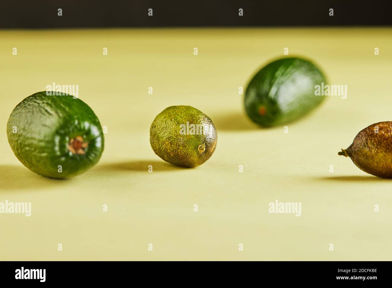 Ripe fresh mini avocados and mini lemons on a yellow background with a ...