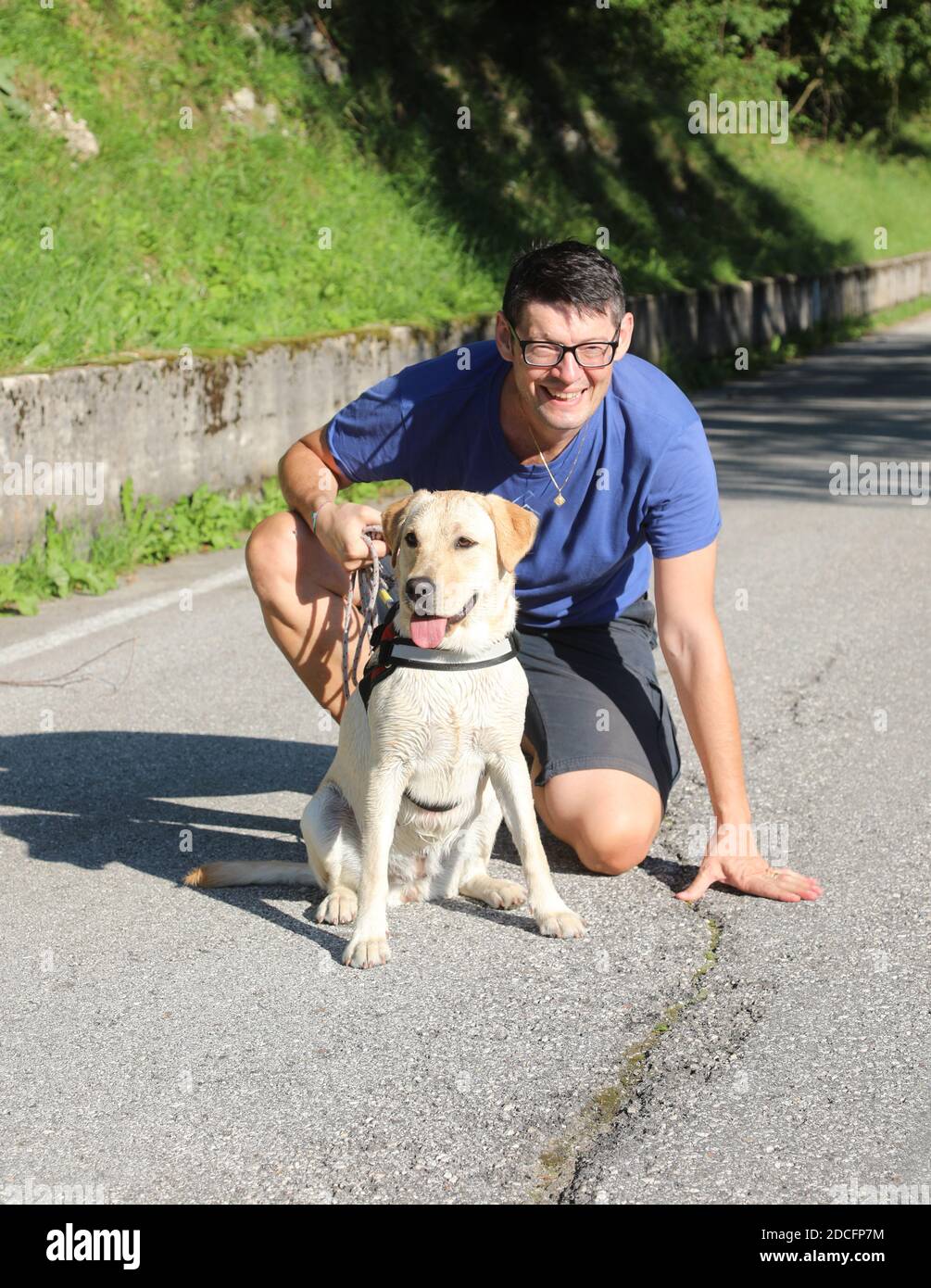 smiling young man with his labrador dog during the walk on the street ...