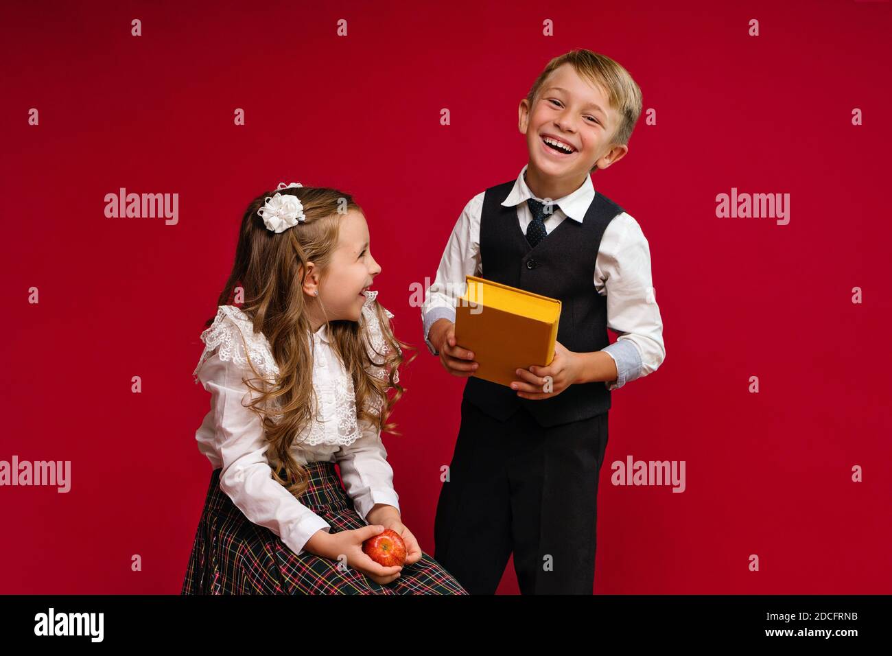 Happy preteen schoolchildren in uniform with books and apple. Success ...