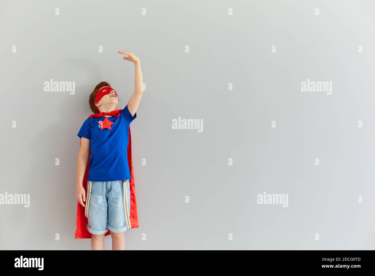 Smiling playful boy in costume of superhero star standing and looking ...