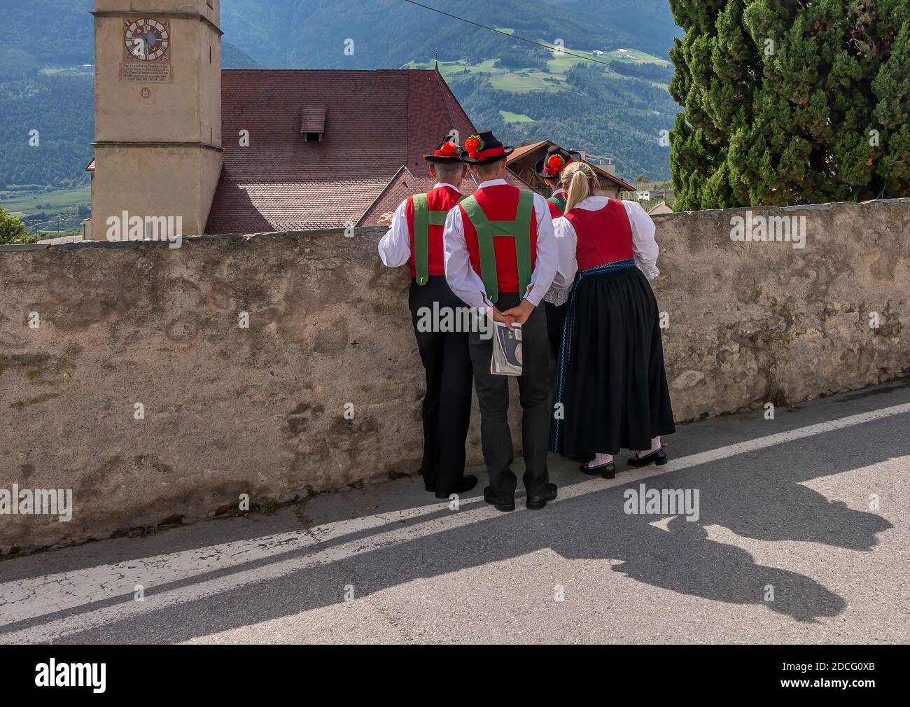 A group of people in traditional Tyrolean clothing looks out from a low ...
