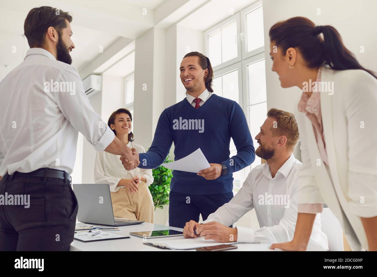 Friendly business team manager shaking hands with happy employee during ...