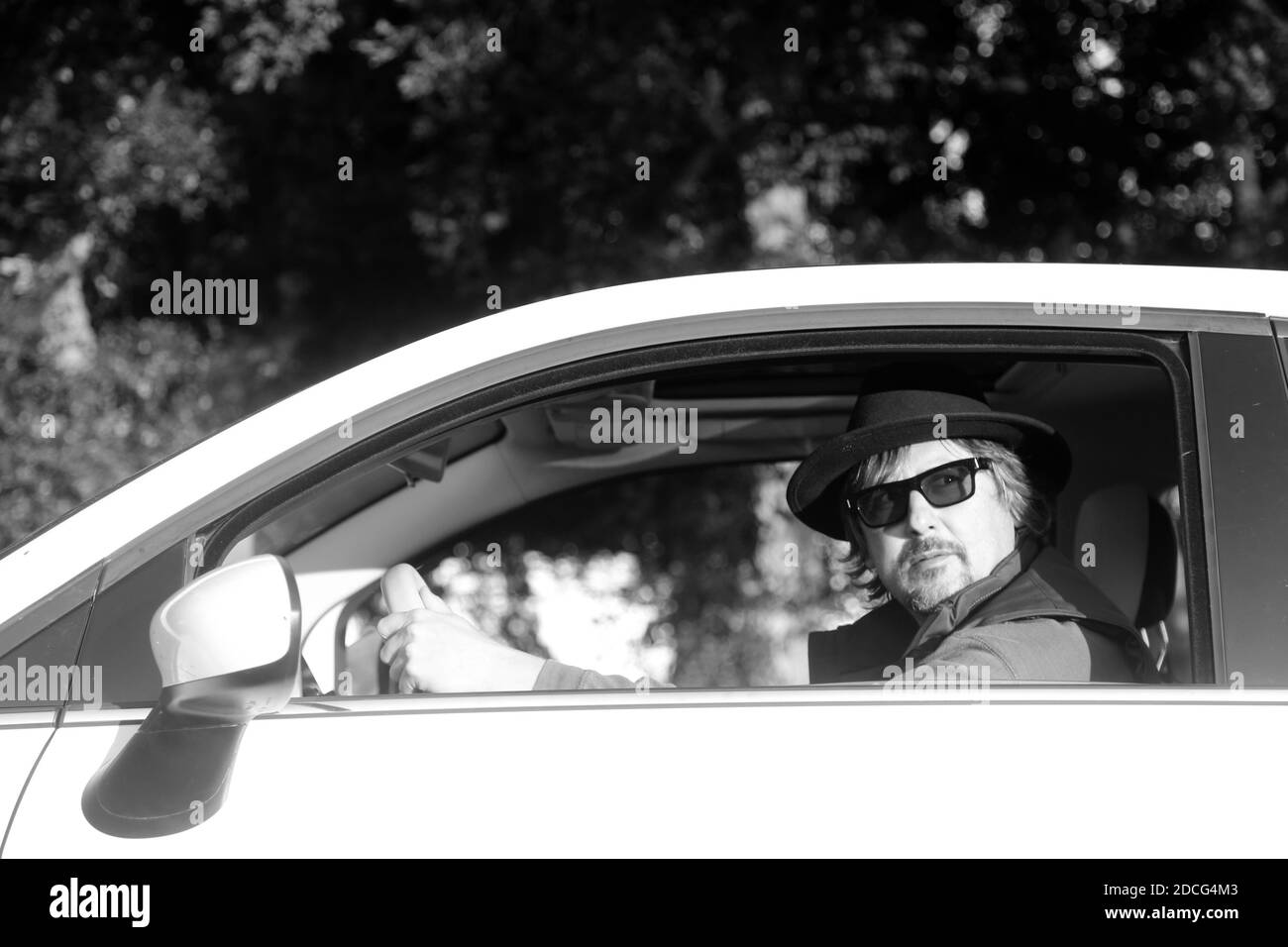 man with hat and sunglasses driving a car in black and white Stock ...