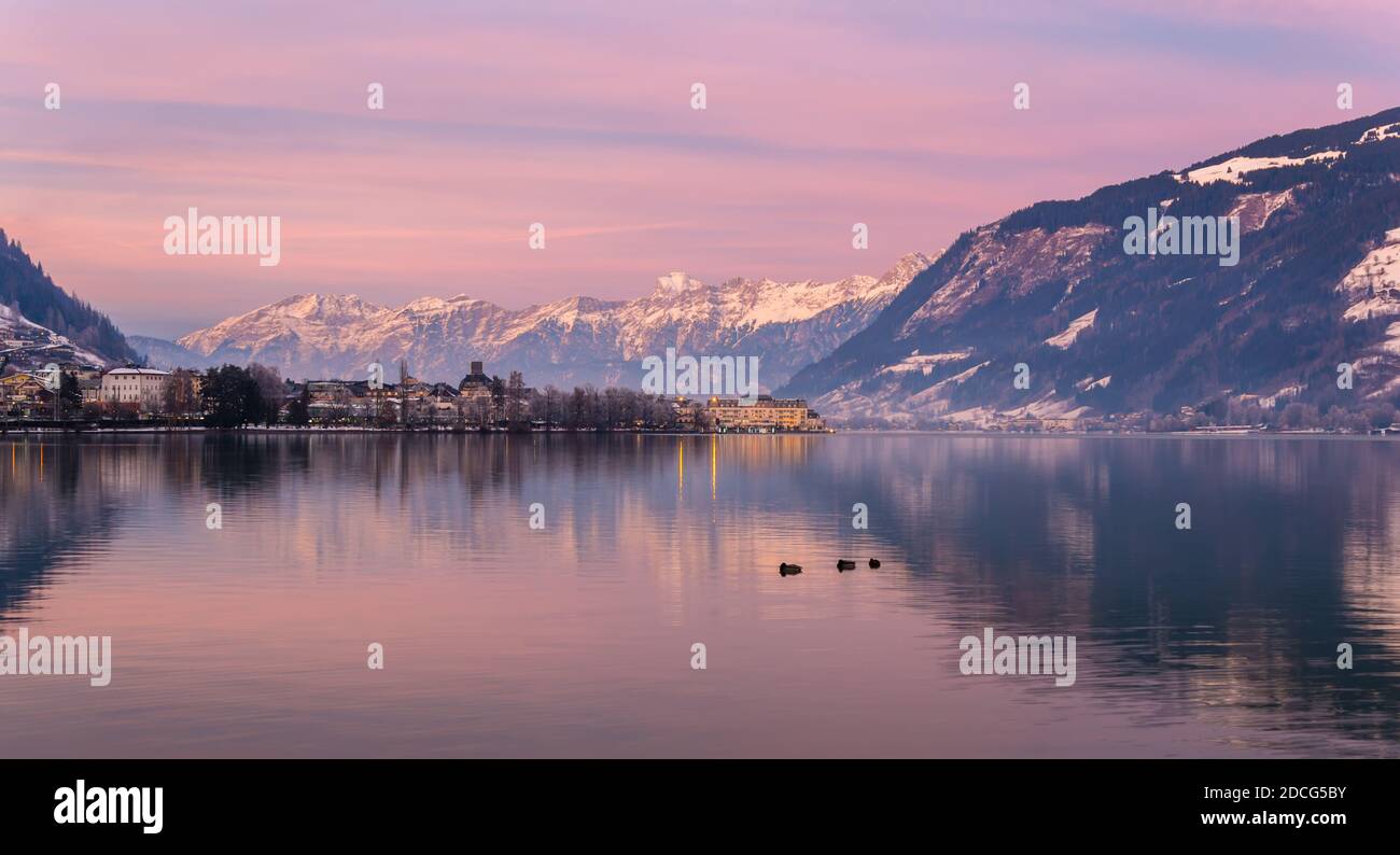 Zell am See in winter evening. View of Lake Zell, town, mountains and ...