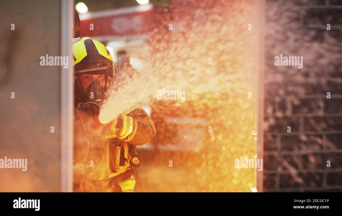 Fireman extinguish fire with the hose. Burning house fire drill. High ...