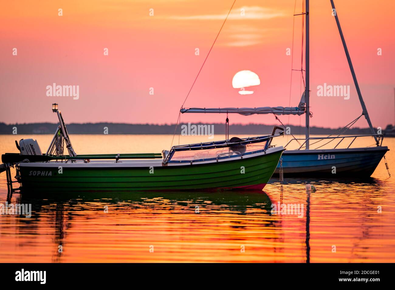 boats on water with sunset in background Stock Photo - Alamy