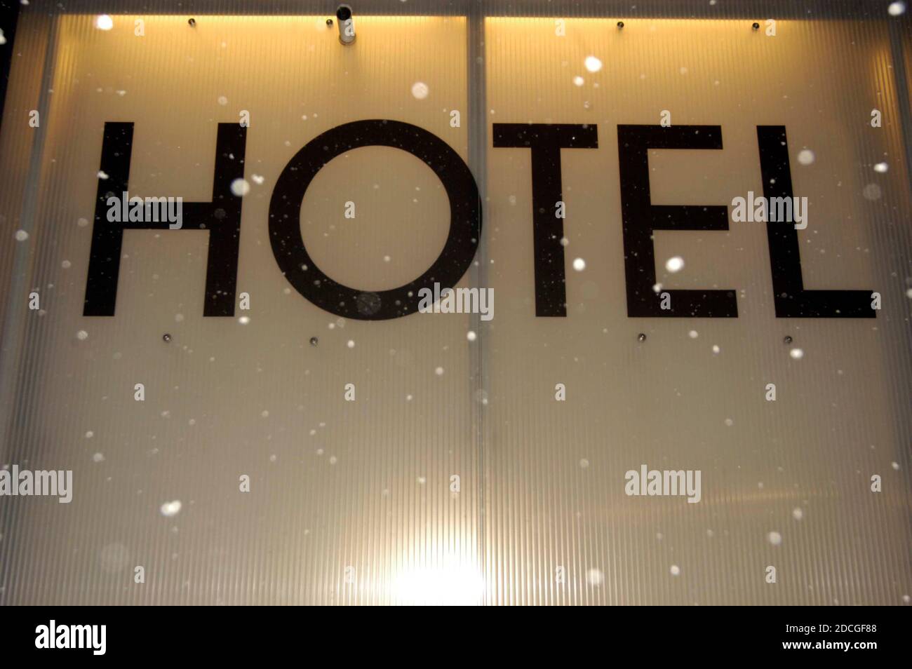a black Hotel sign with snow falling down in front of it Stock Photo ...