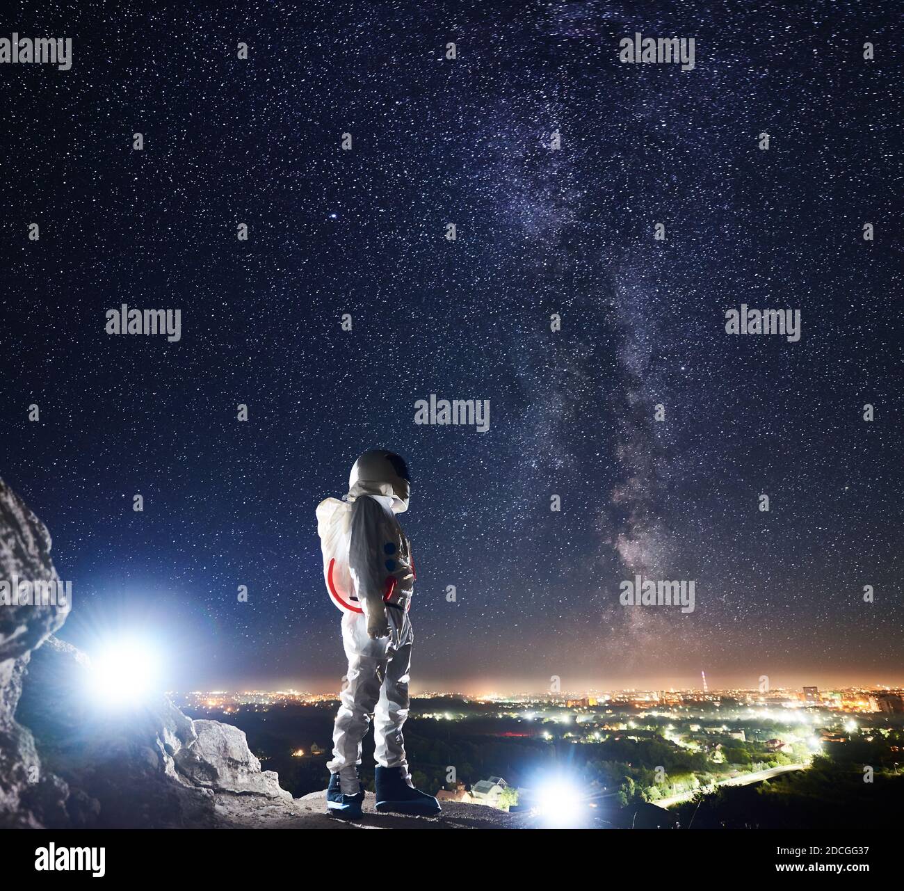 Mission specialist spaceman standing on rocky hill and looking at ...