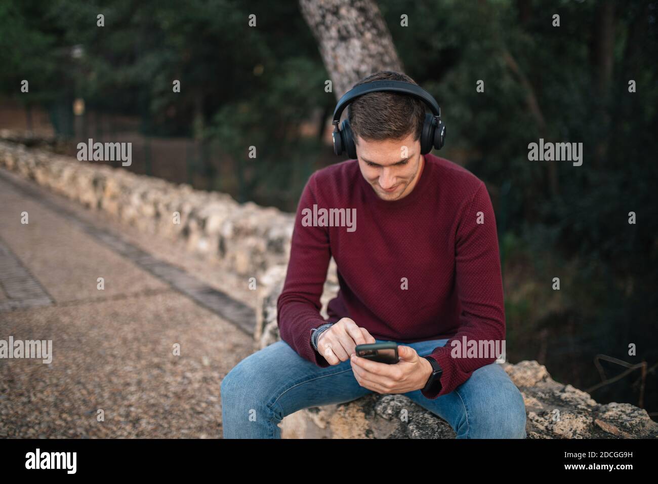 Boy listening to music with wireless headphones and using his cell ...