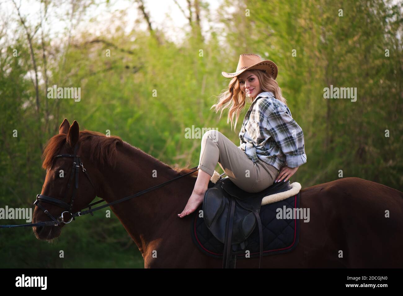 Beautiful girl in a hat riding a horse in countryside Stock Photo - Alamy