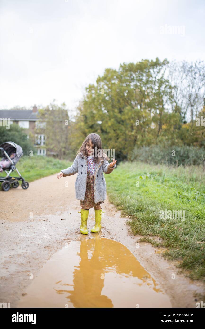 Happy little girl looking at muddy puddle before jumping in it Stock ...
