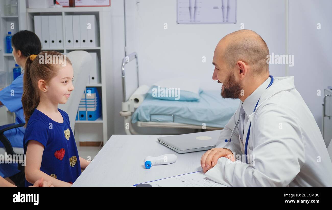 Friendly doctor doing high five with child sitting at the desk ...