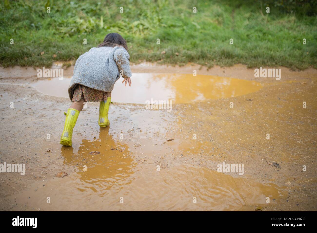 Happy little girl taking momentum before jumping in a muddy puddle Stock Photo - Alamy
