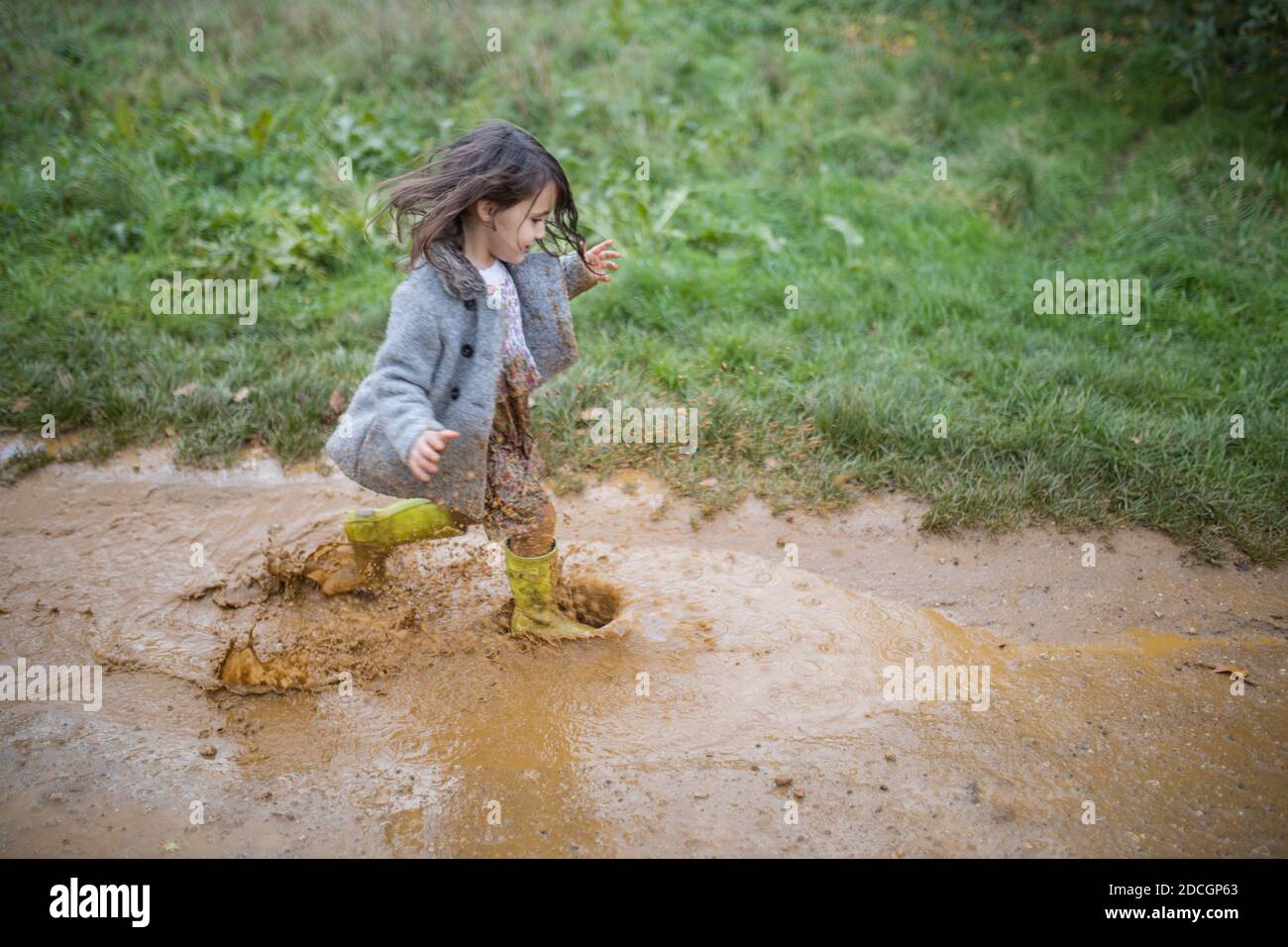 Happy little girl splashing and running through a muddy puddle Stock ...