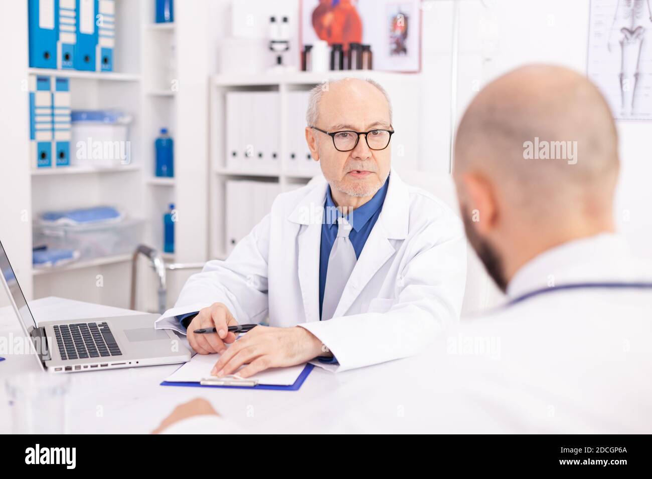 Experienced mature doctor explaining patient diagnosis to young medical ...