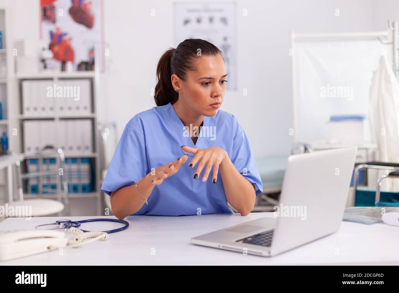 Nurse in hospital office reading pacient treatment on laptop. Health ...