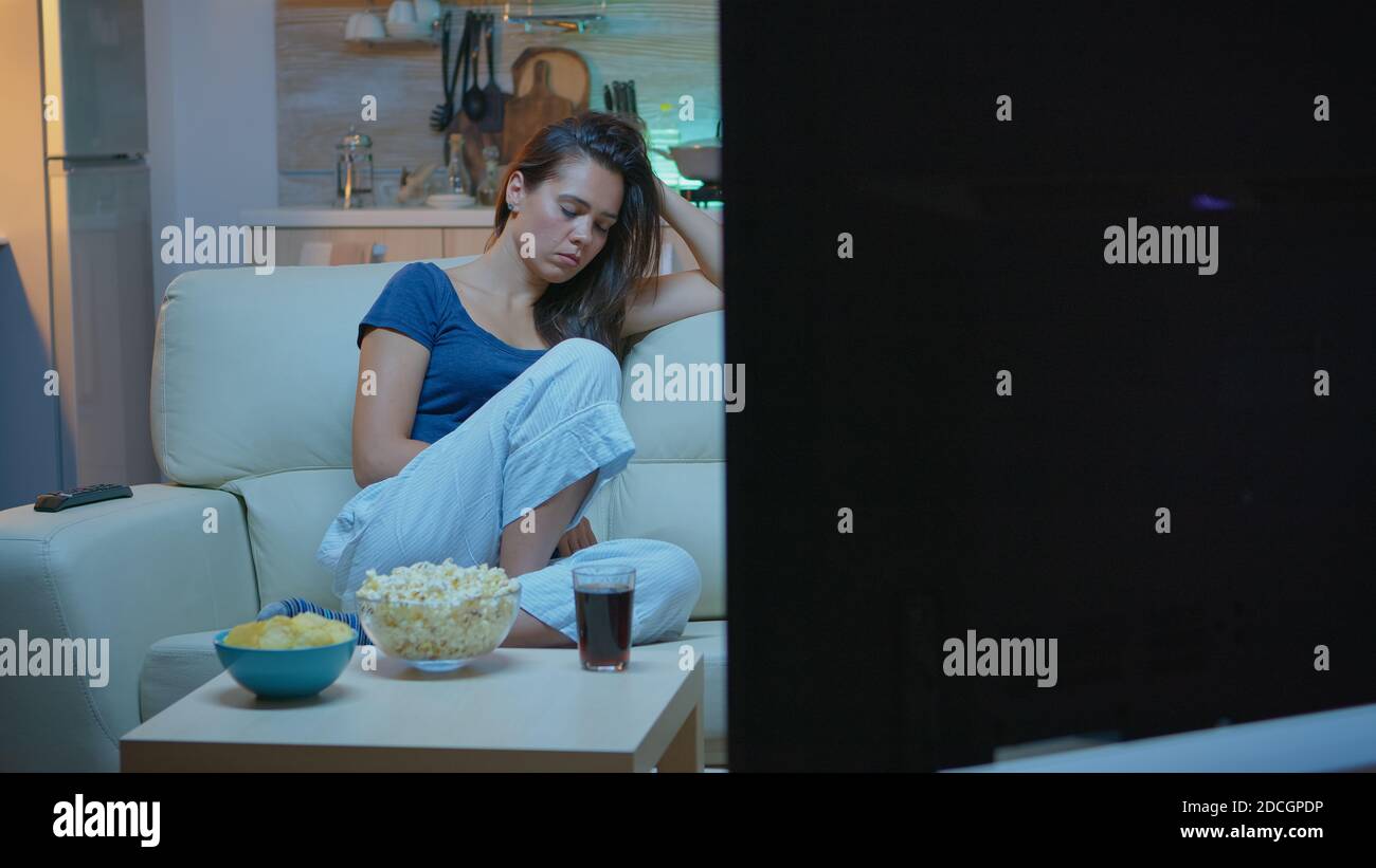 Caucasian woman falling asleep on sofa at home while watching TV. Tired ...