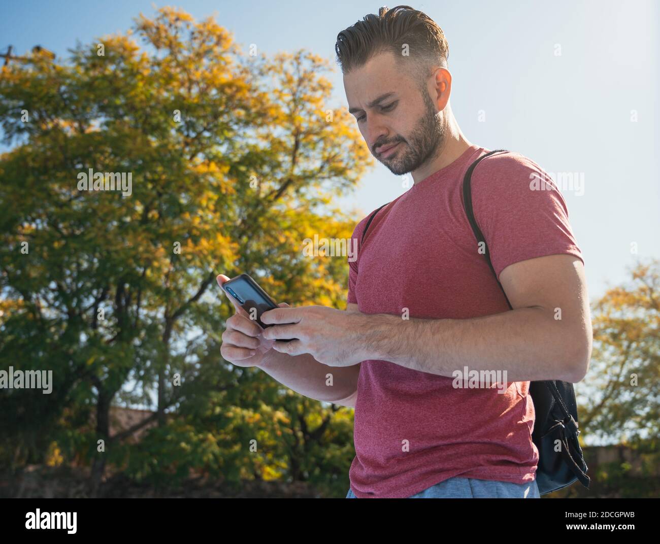 A low angle shot of a young man checking his phone before training ...