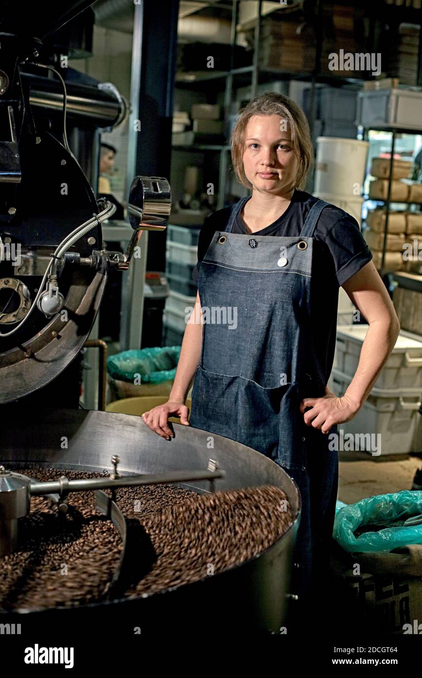 Young female coffee roaster checks coffee beans during roasting Stock ...