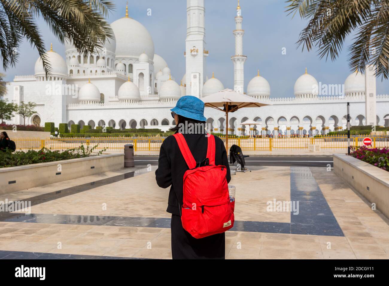 A Chinese female Tourist visiting white Grand Mosque against blue sky ...