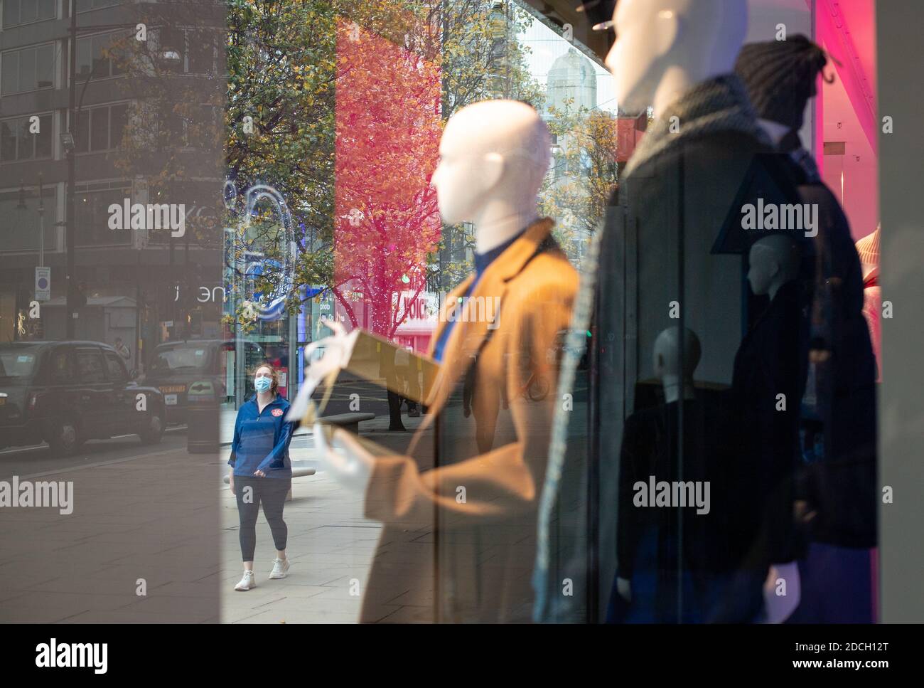 A woman wearing a face mask walks down a quiet Oxford Street, in London ...