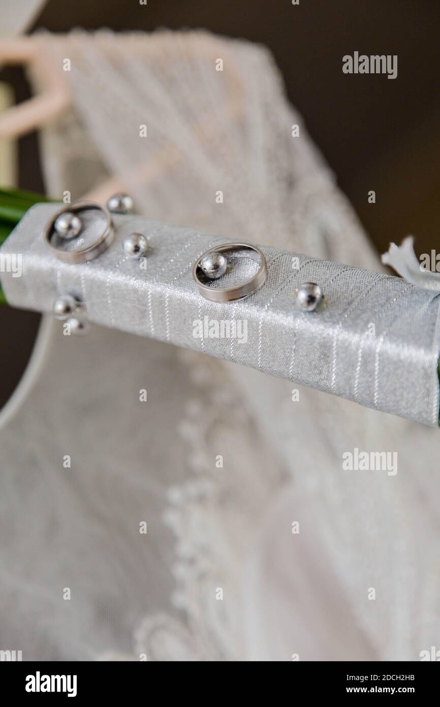 a vertical closeup of silver wedding rings on a white narrow object ...