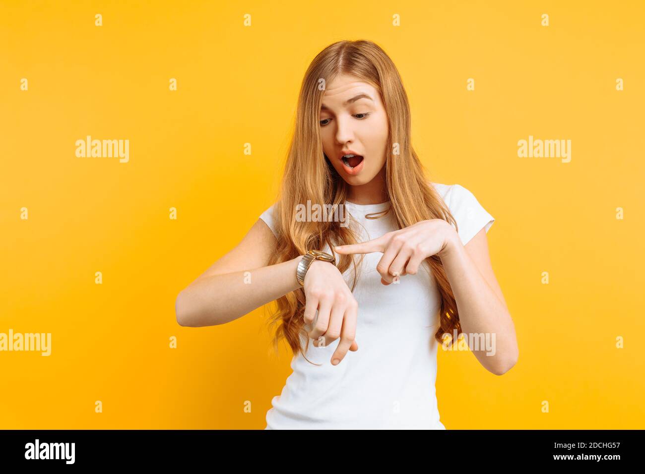 beautiful girl looking at a hand watch, points to the watch, on a ...