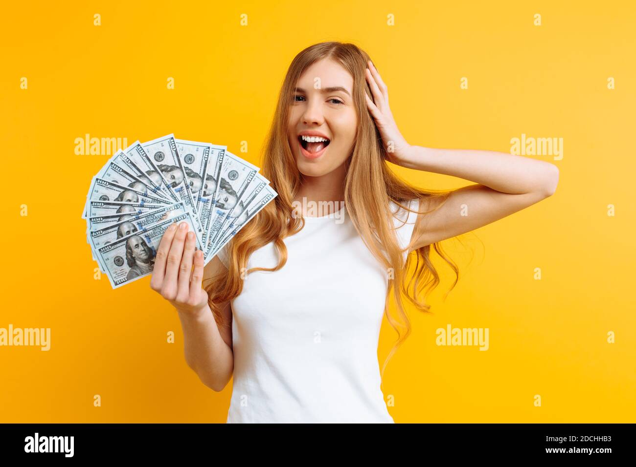 Portrait of a happy contented girl in white t-shirt holding a pile of ...