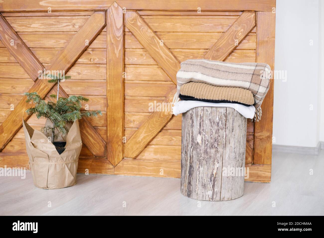 Christmas tree in a craft bag and blankets on the stump. Home decor ...