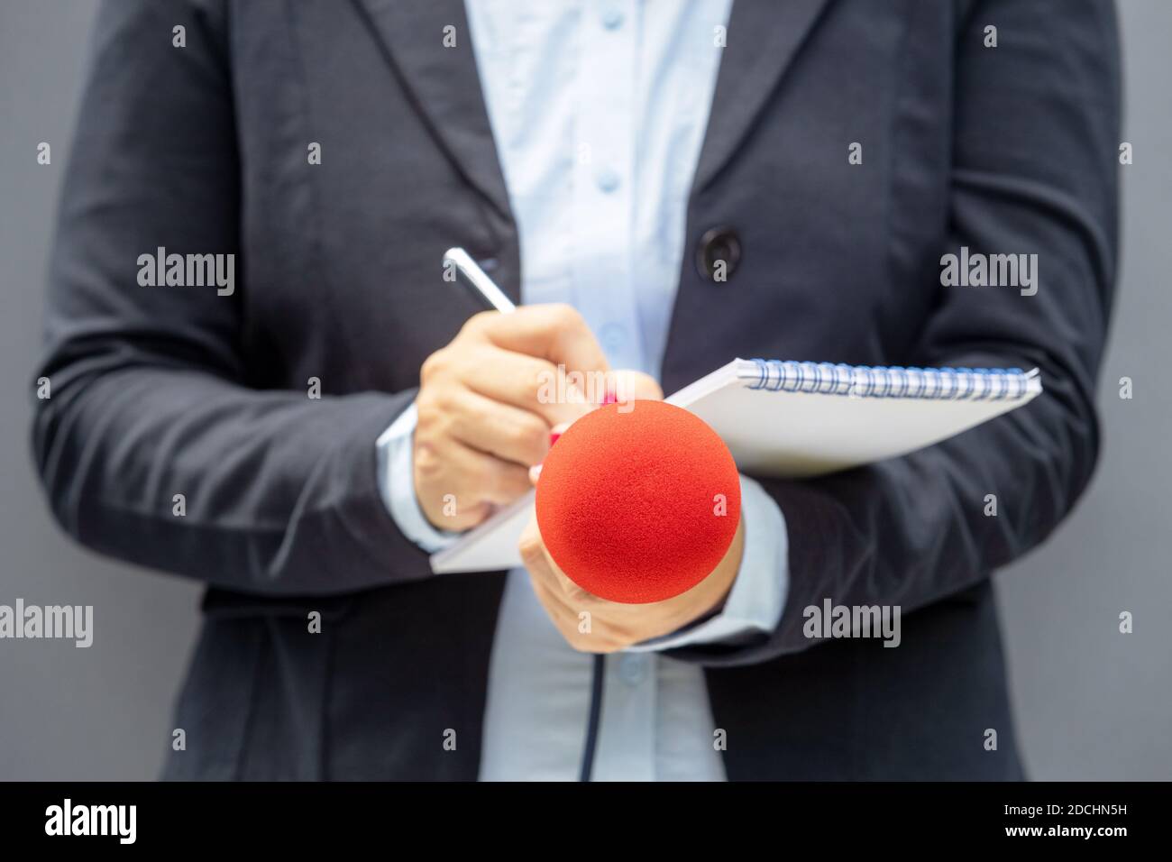 Female reporter at press conference or media event, writing notes ...