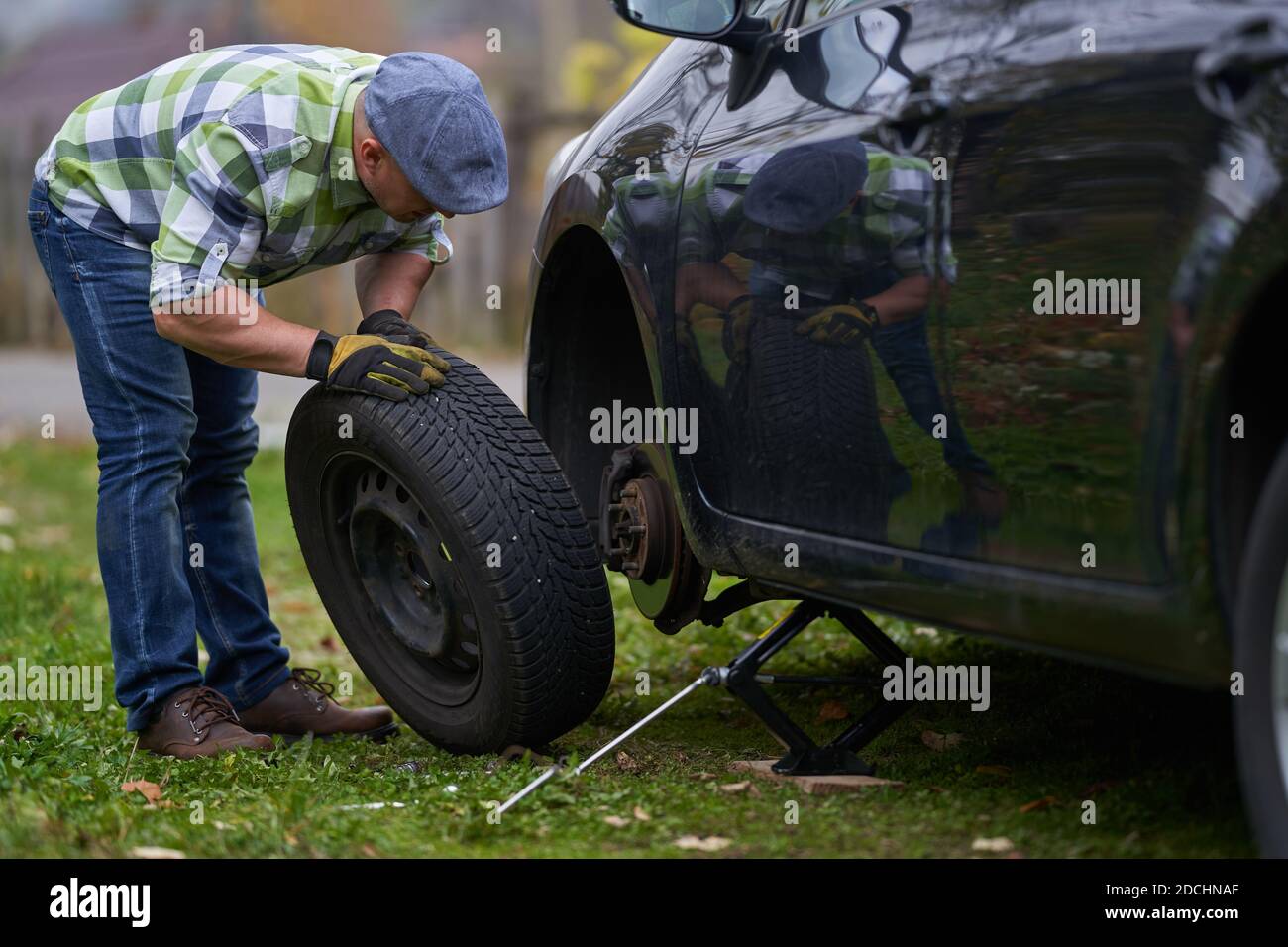 Man changing a flat tyre on his car by himself Stock Photo - Alamy