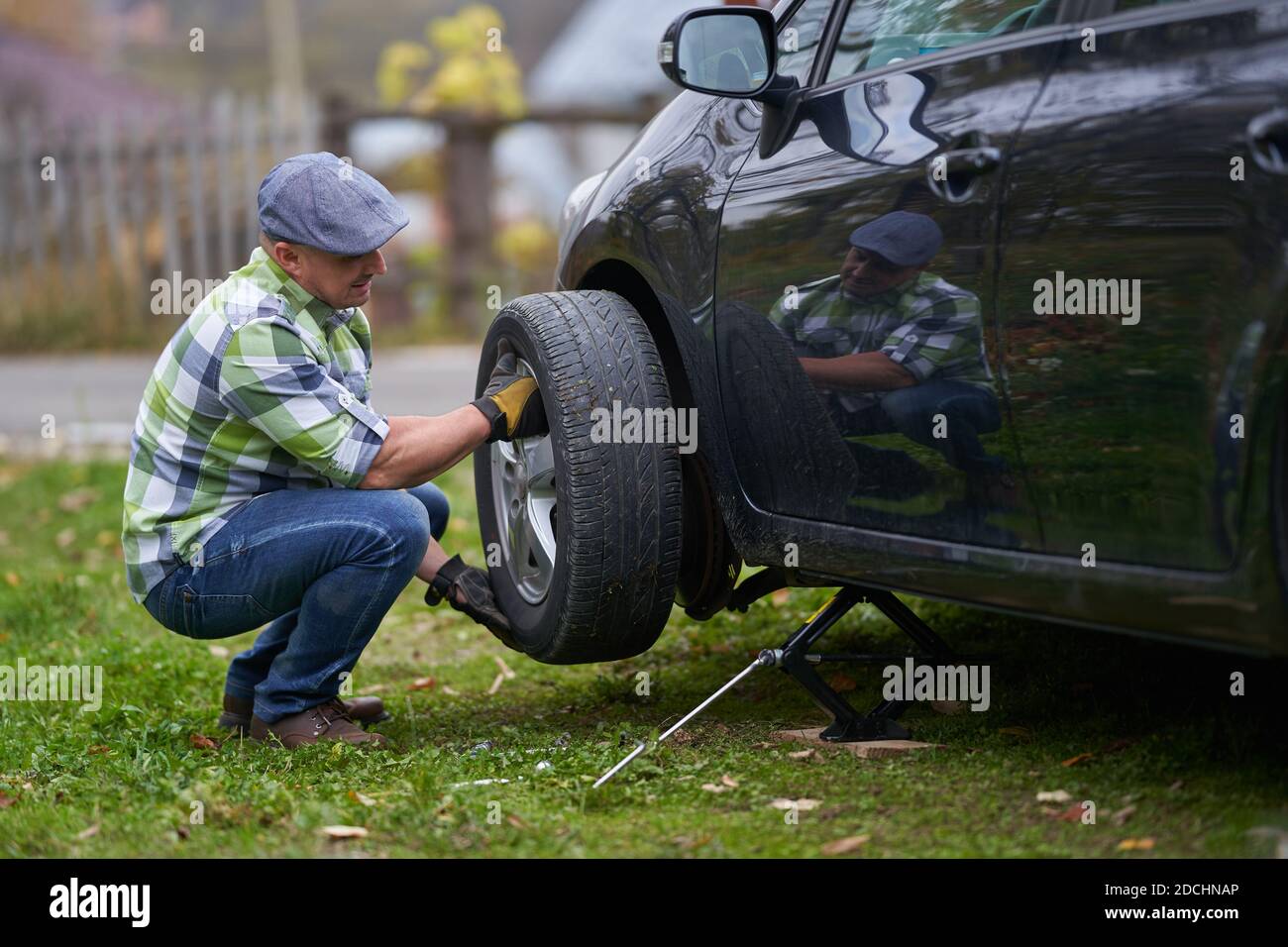 Man changing a flat tyre on his car by himself Stock Photo - Alamy