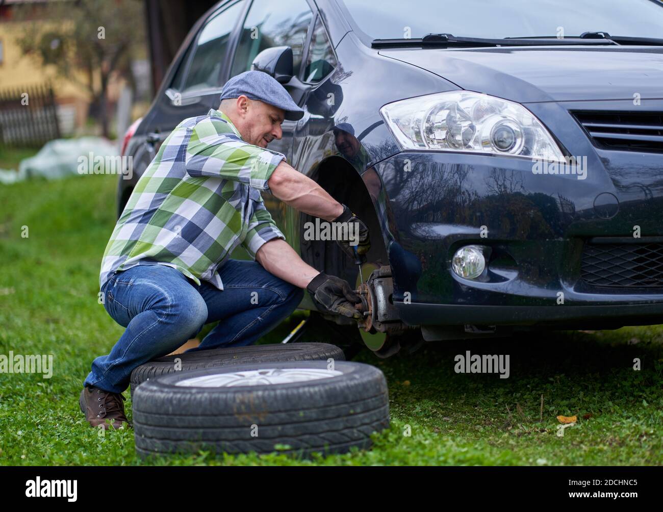 Man changing a flat tyre on his car by himself Stock Photo - Alamy