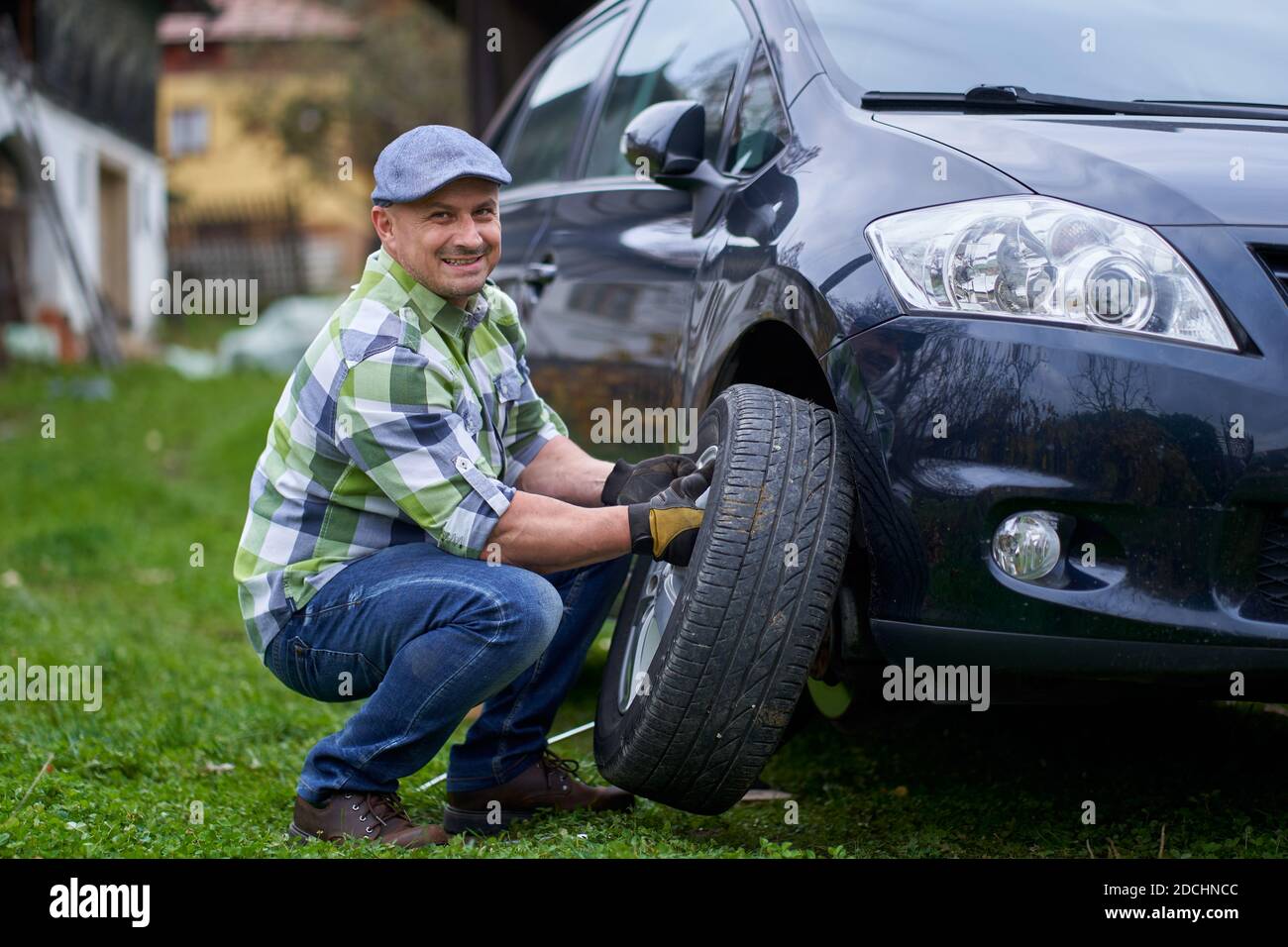 Man changing a flat tyre on his car by himself Stock Photo - Alamy
