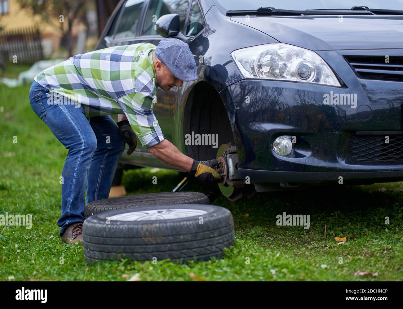 Man changing a flat tyre on his car by himself Stock Photo - Alamy