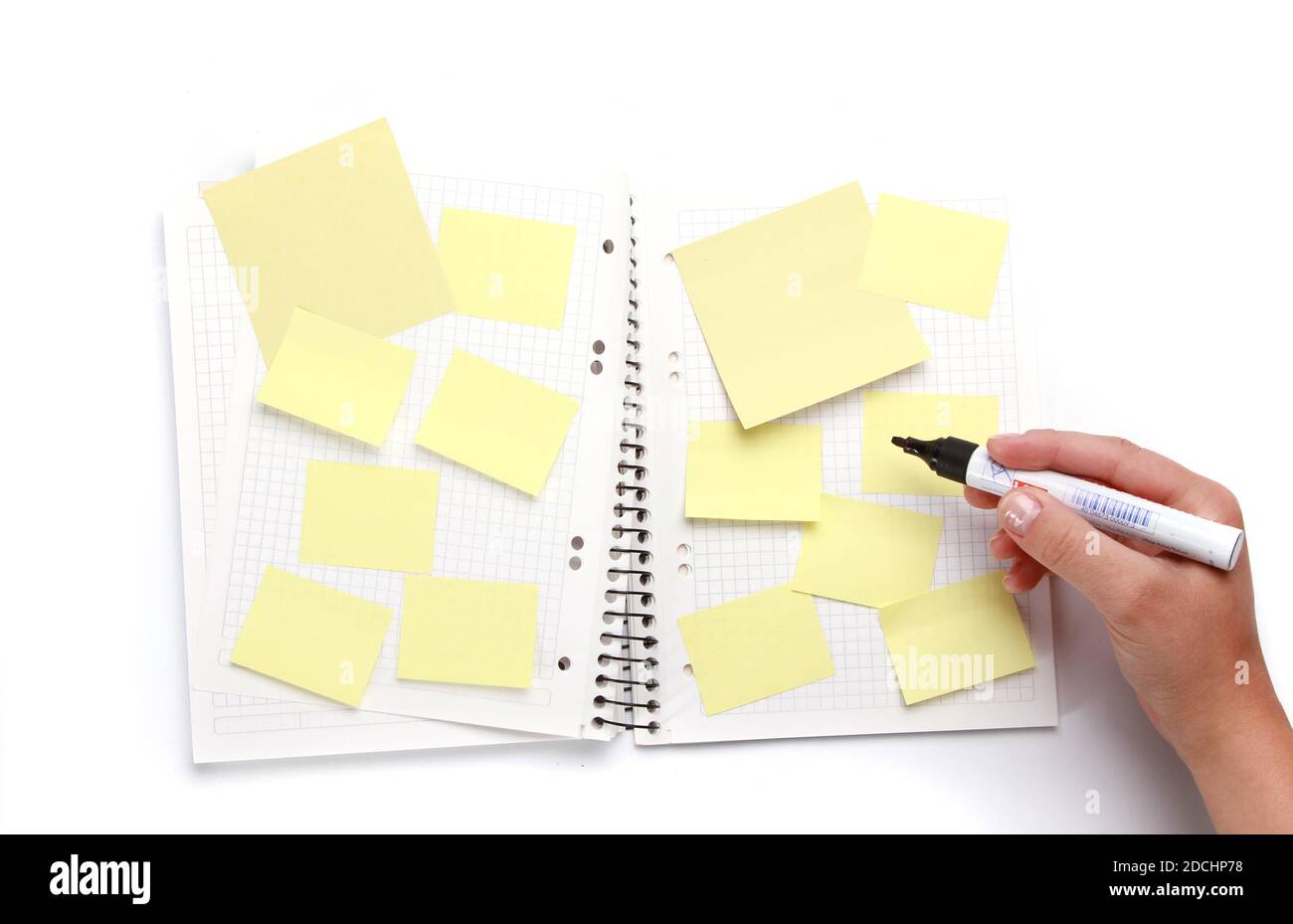 A hand, writing with a marker on sticky notes in an exercise book ...