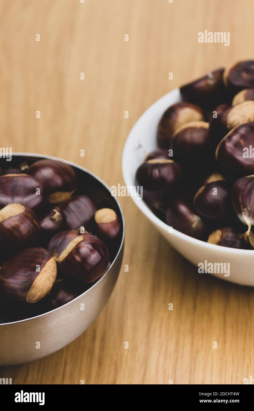 A vertical shot of fresh chestnuts on a bowl on a wooden table Stock ...