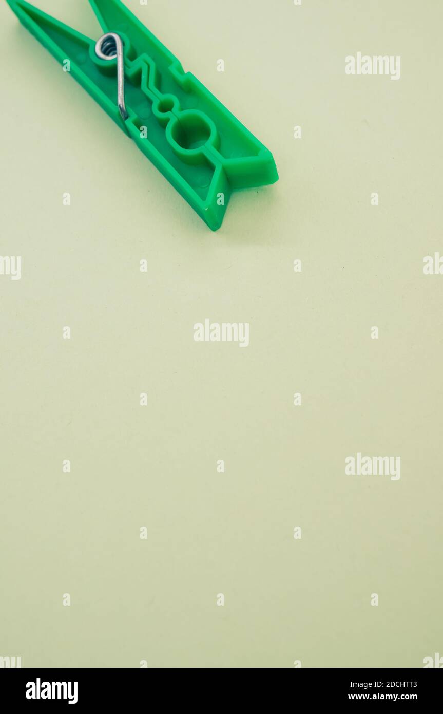 A vertical shot of green plastic clothespin isolated on a light ...