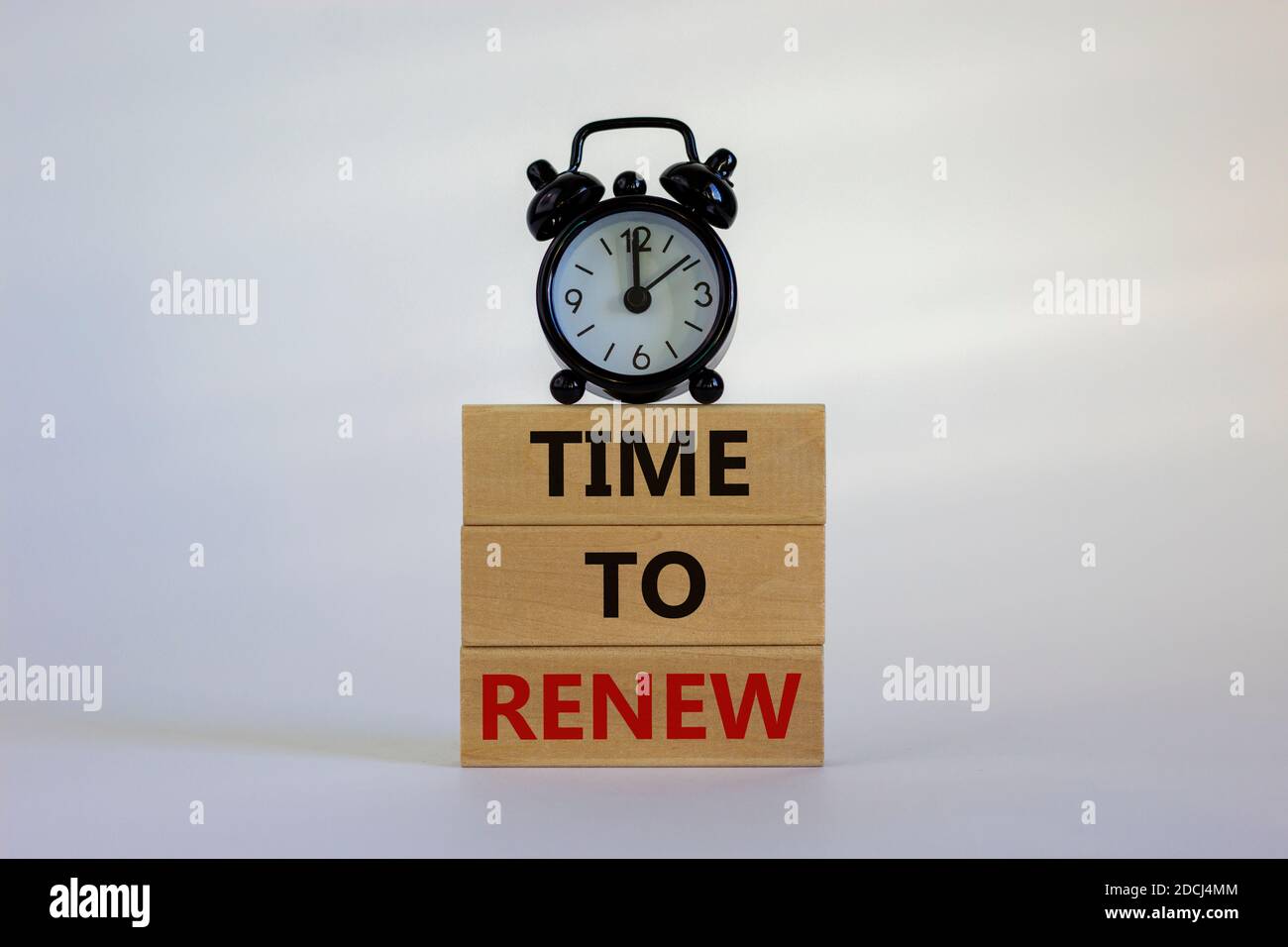 Wooden blocks with words 'time to renew'. White table. Black alarm ...