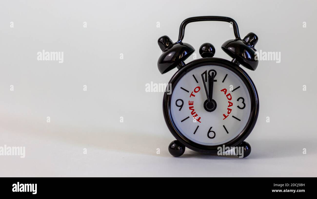 Time to adapt concept. Beautiful black alarm clock with words 'time to ...