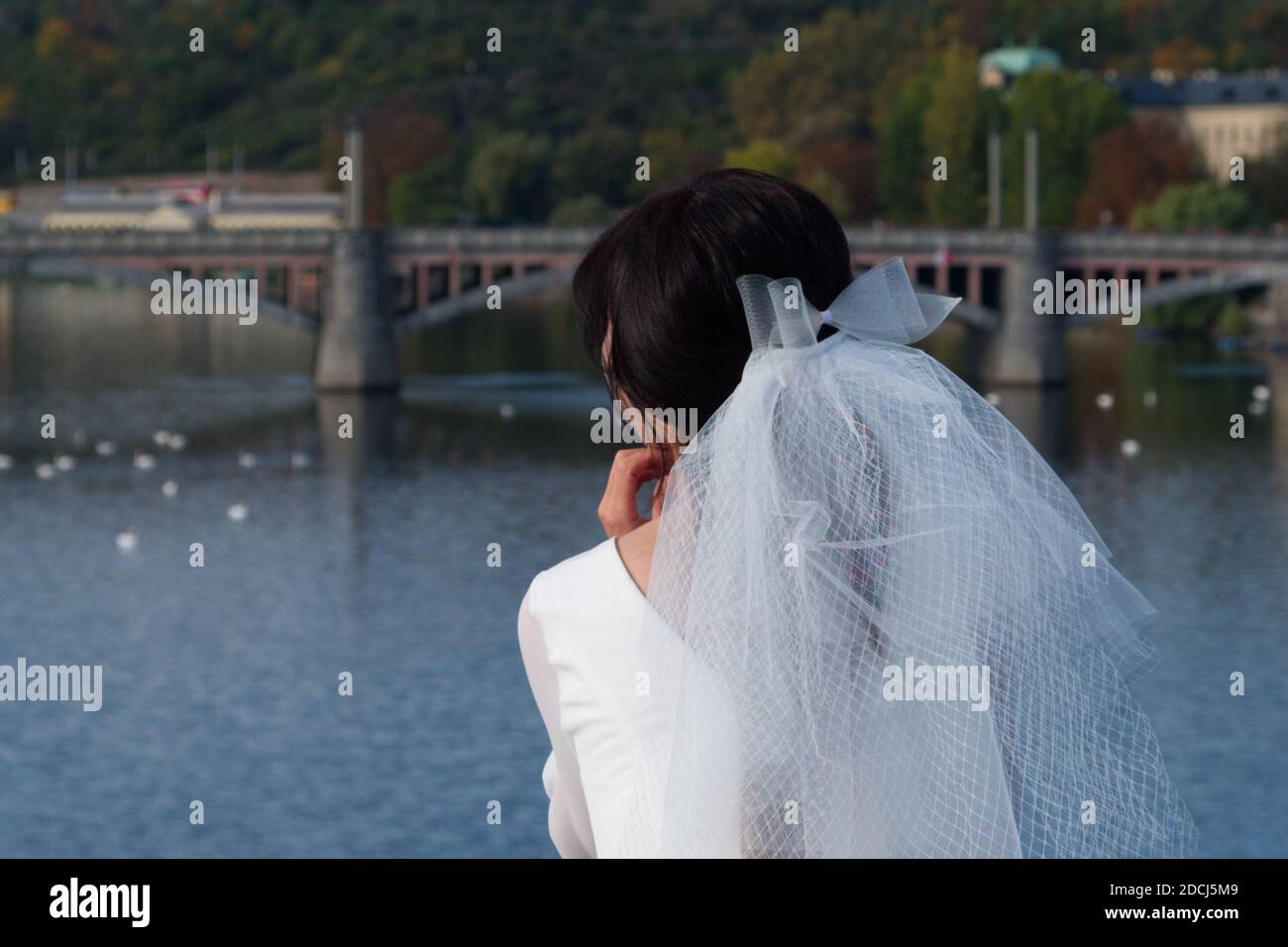 The bride admires Prague from Charles Bridge. Girl in a wedding dress ...