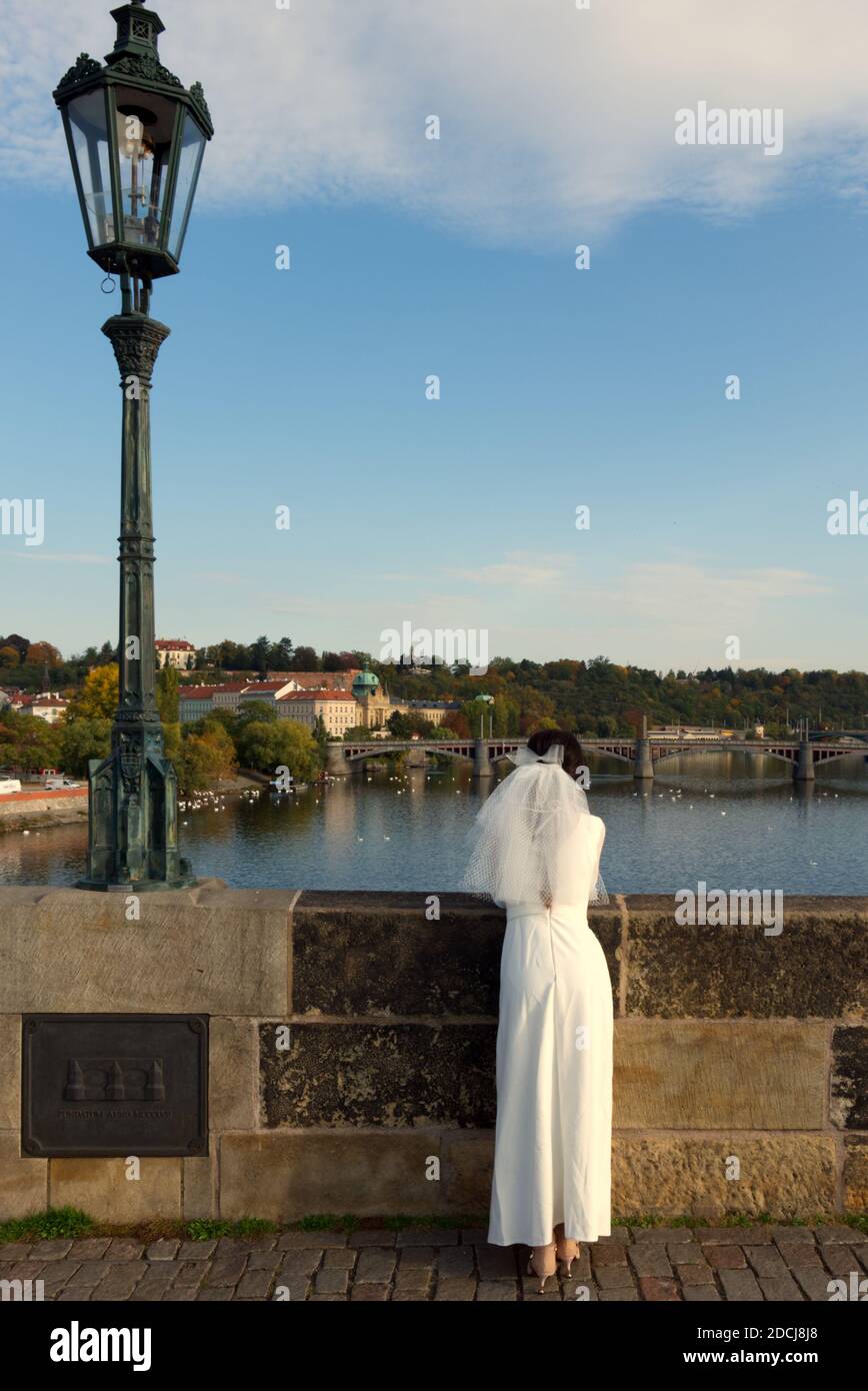 The bride admires Prague from Charles Bridge. Girl in a wedding dress ...