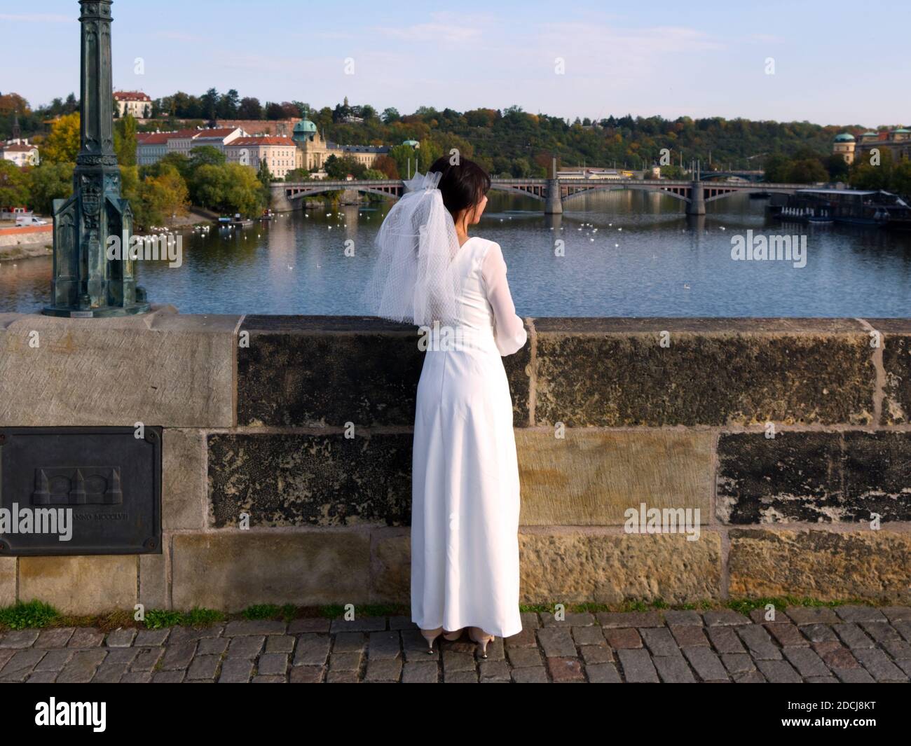 The bride admires Prague from Charles Bridge. Girl in a wedding dress ...