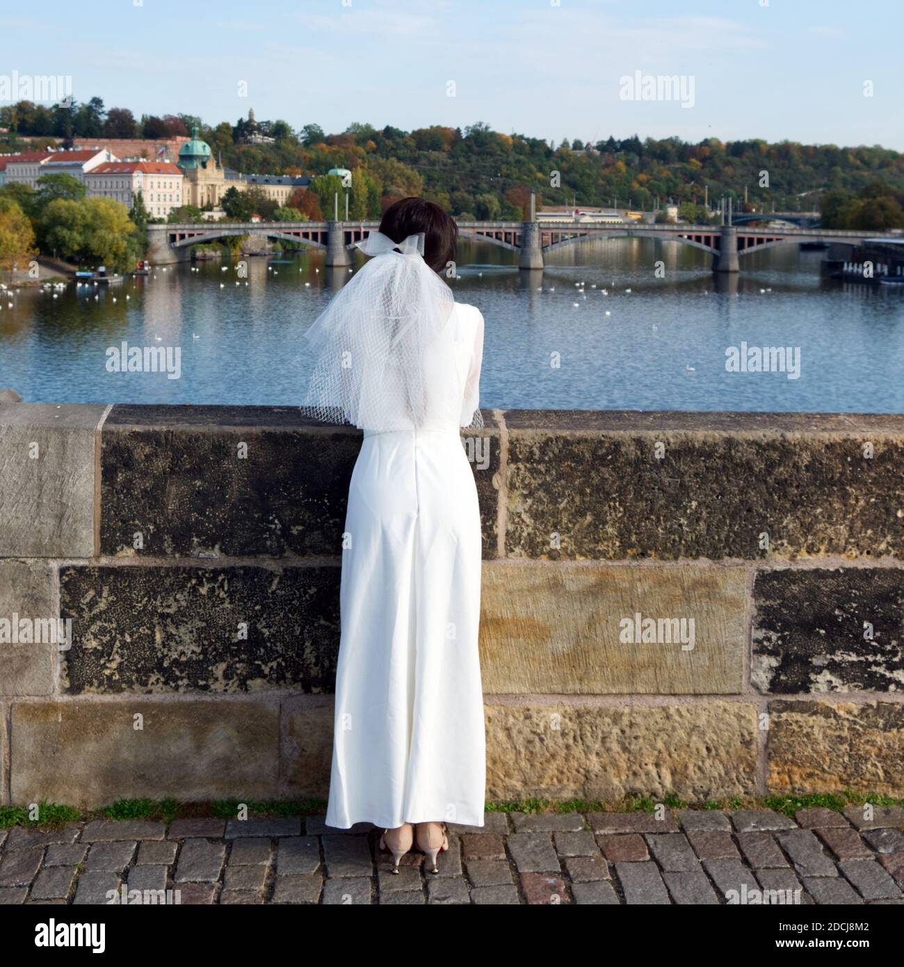 The bride admires Prague from Charles Bridge. Girl in a wedding dress ...