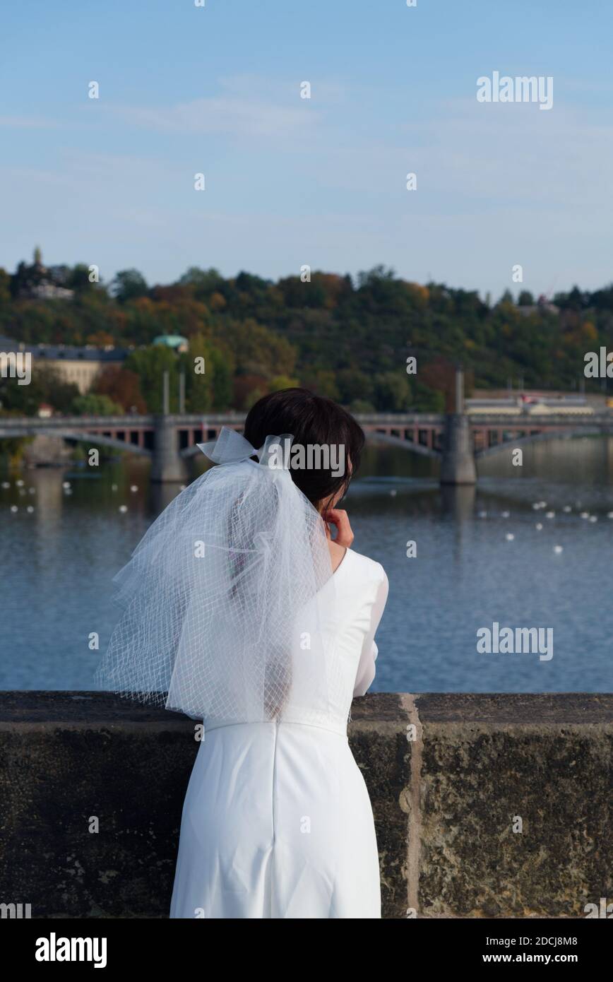 The bride admires Prague from Charles Bridge. Girl in a wedding dress ...